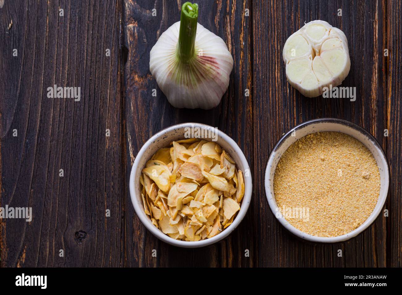 Overhead garlic powder and flakes with piece of garlic over wooden ...