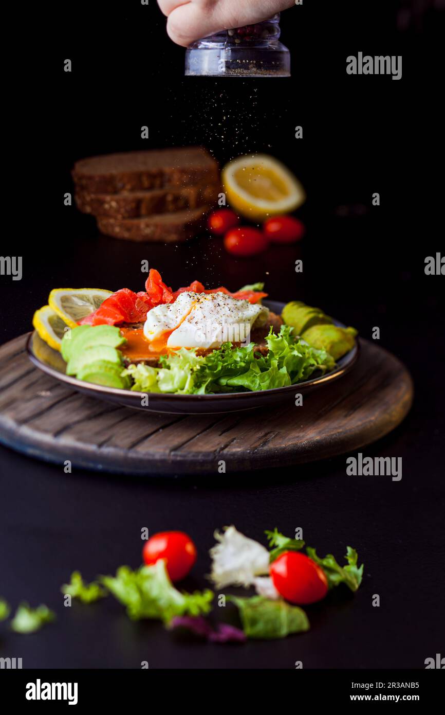 Hand spilling pepper mix over breakfast, black background Stock Photo ...