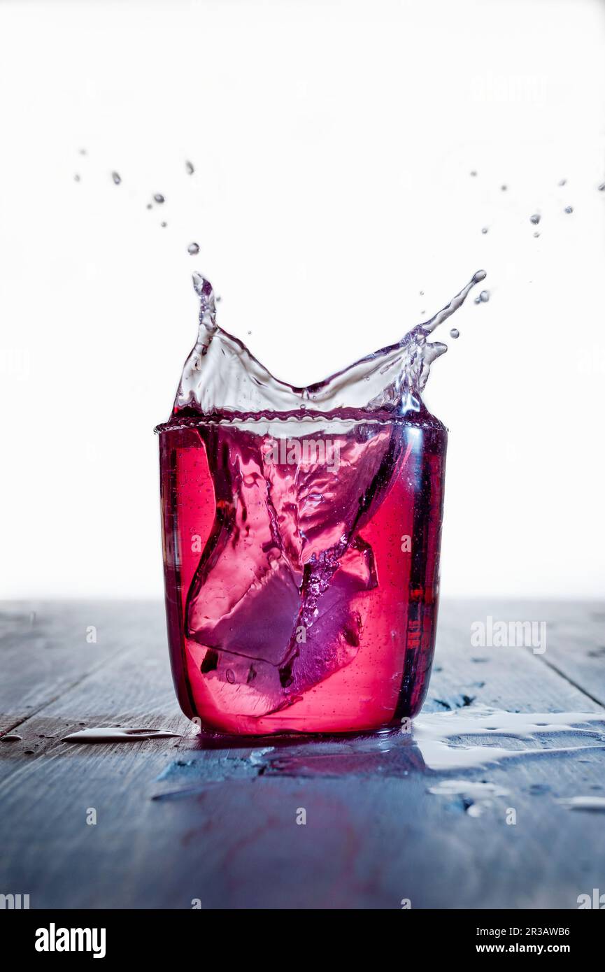 A red drink splashing against a white background Stock Photo - Alamy