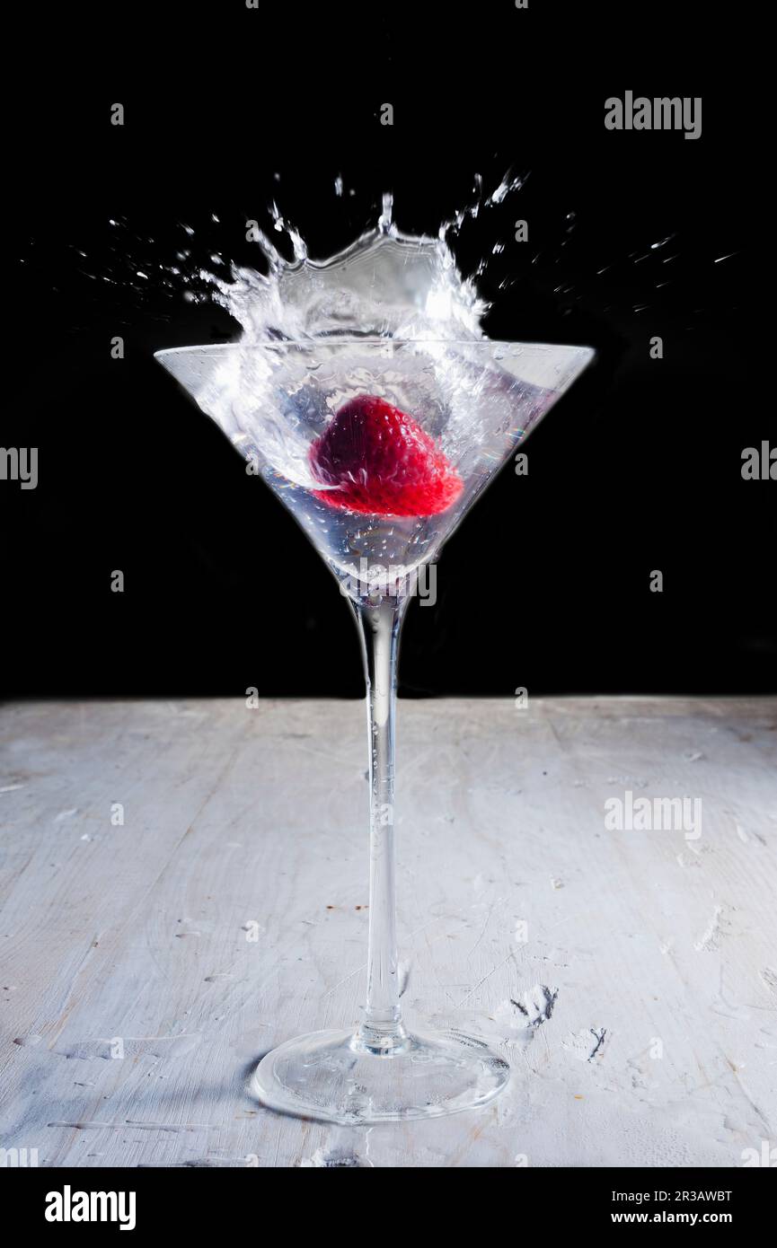 A drink with with a strawberry and a splash against a black background ...