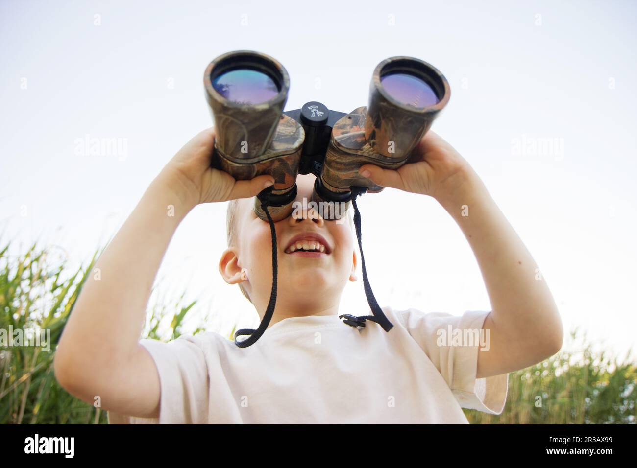 Portrait of little boy looking through binoculars on river bank. Cute ...