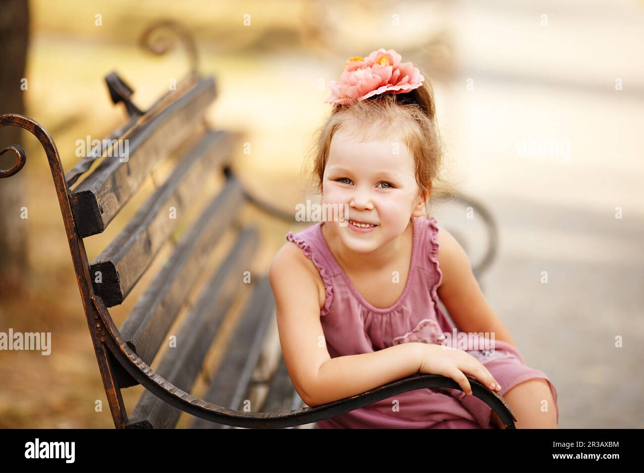 Portrait of a smiling pretty little girl sitting on a park bench Stock ...