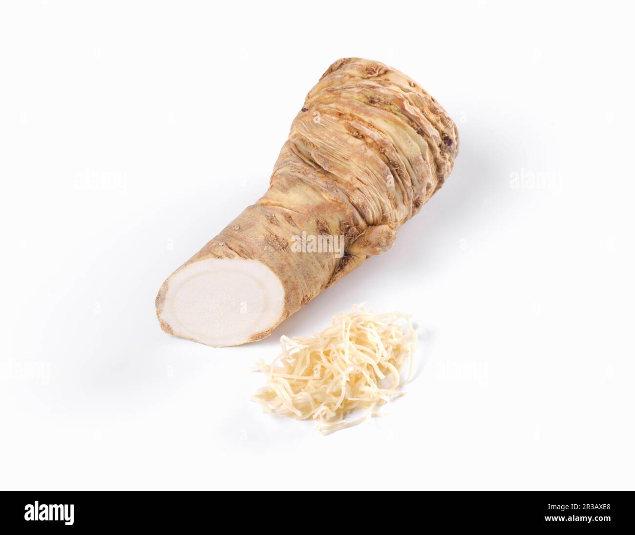 A piece of horseradish root and grated horseradish on a white ...