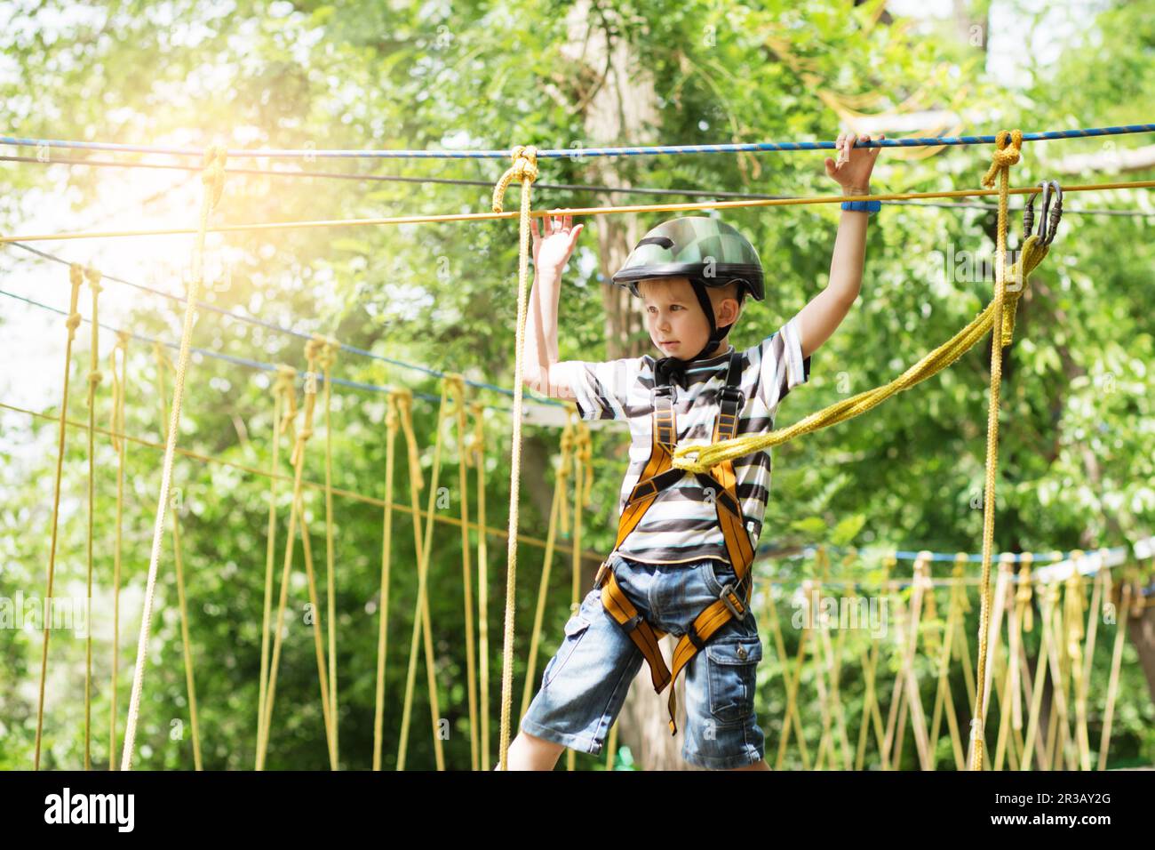 Kids climbing in adventure park. Boy enjoys climbing in the ropes ...