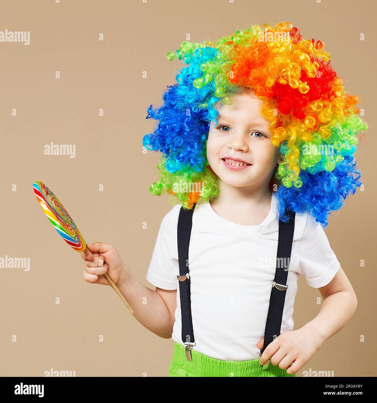 Happy clown boy in large colorful wig. Let's party! Funny kid clown. 1 ...