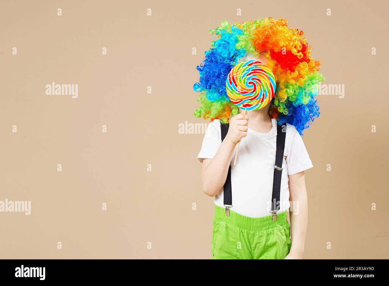 Happy clown boy in large colorful wig. Let's party! Funny kid clown. 1 ...
