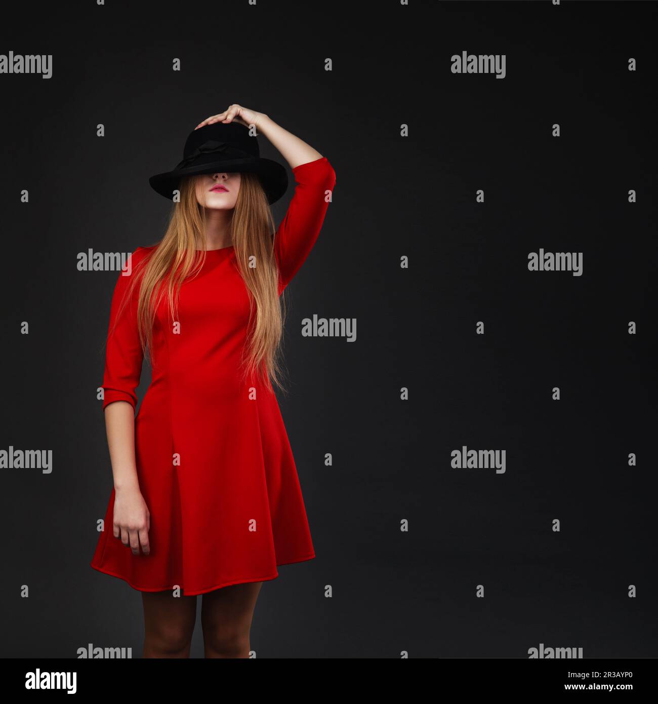 A beautiful girl dressed in red holding her hat. Girl holding hat up to ... A beautiful girl dressed in red holding her hat. Girl holding hat up to ...