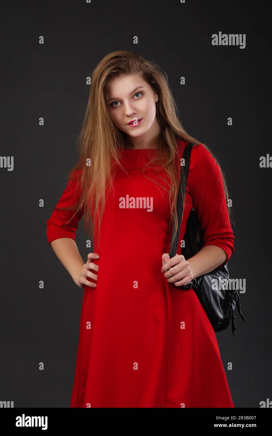 Portrait of a girl in a red dress with a black leather backpack on her ...
