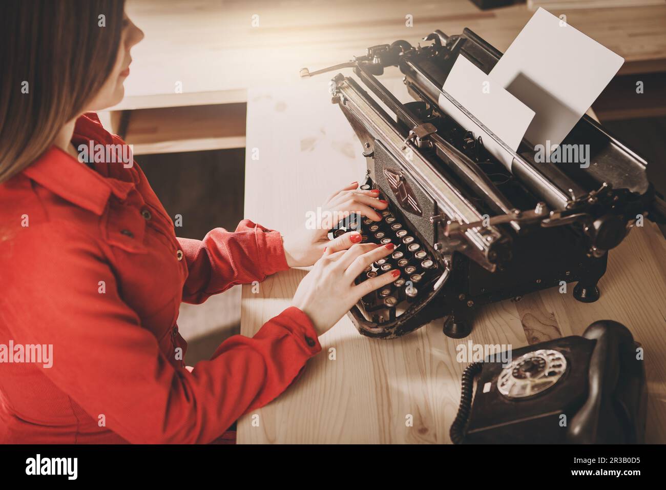Secretary at old typewriter with telephone. Young woman using ...
