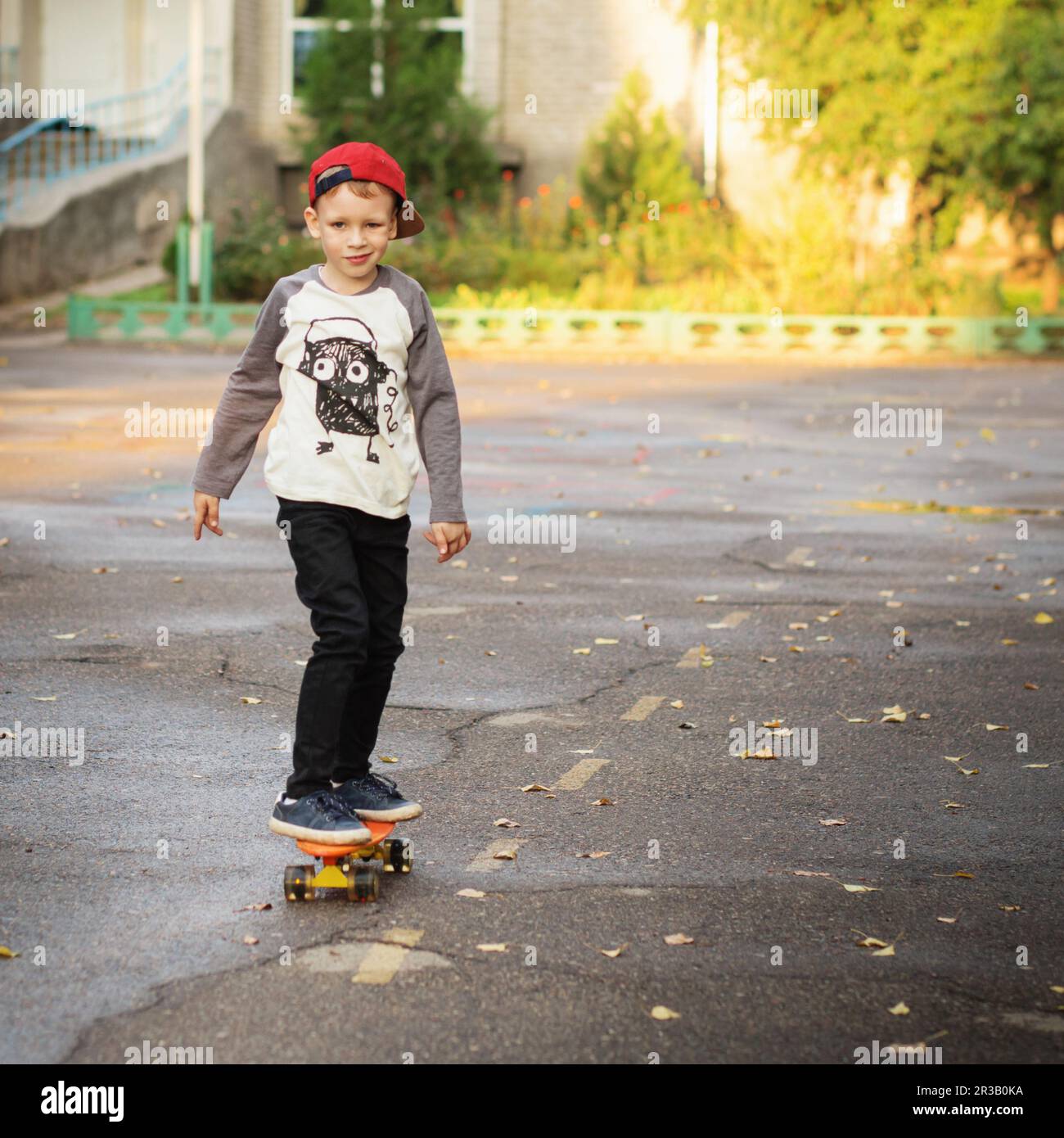 Little urban boy with a penny skateboard. Young kid riding in the park ...