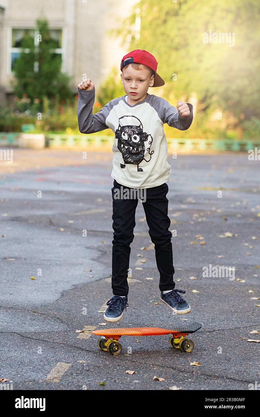 Little urban boy with a penny skateboard. Young kid riding in the park ...