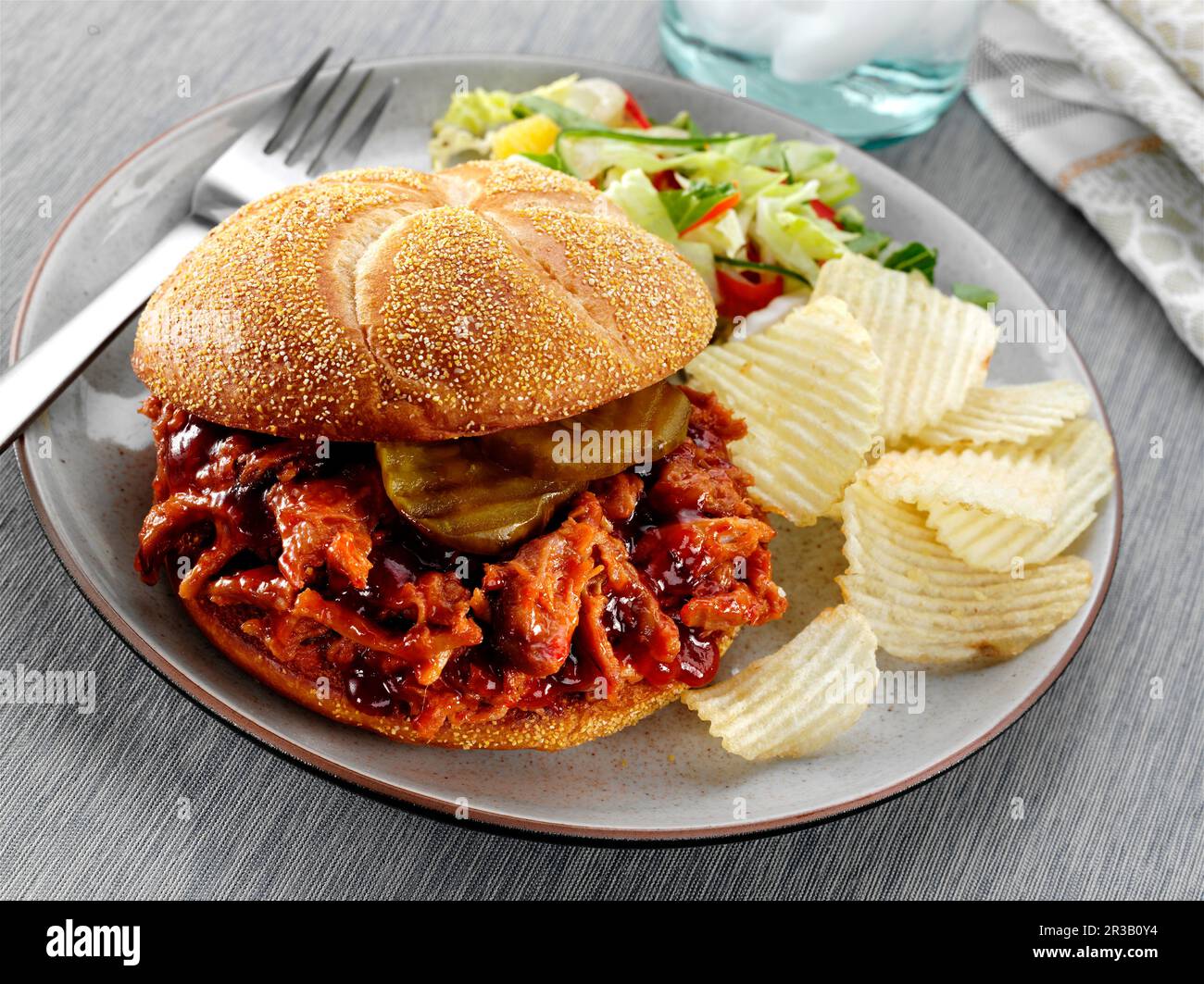 Shredded BBQ Pork with pickles on a Kaiser Roll bun served with potato ...