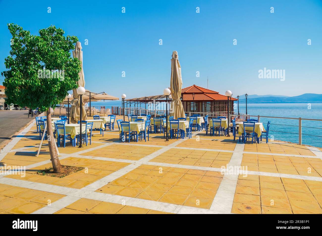 Empty tavern restaurant by the seafront with wooden chairs and tables ...