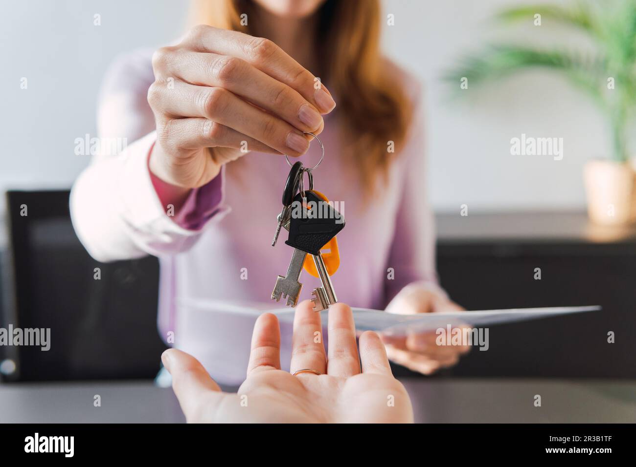 Real estate agent giving house keys to customer in office Stock Photo ...
