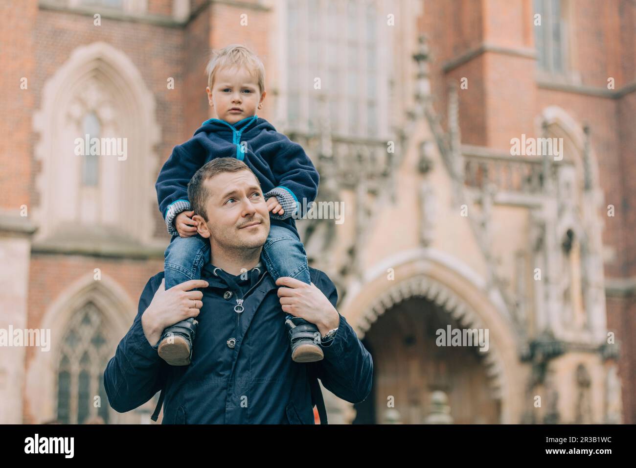 Father carrying son on shoulders in front of cathedral Stock Photo - Alamy