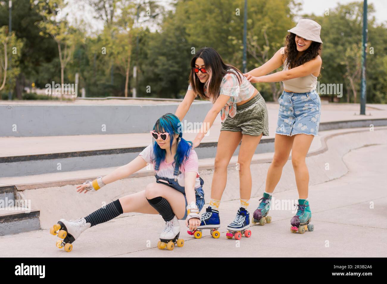 Young friends roller skating together in park Stock Photo - Alamy