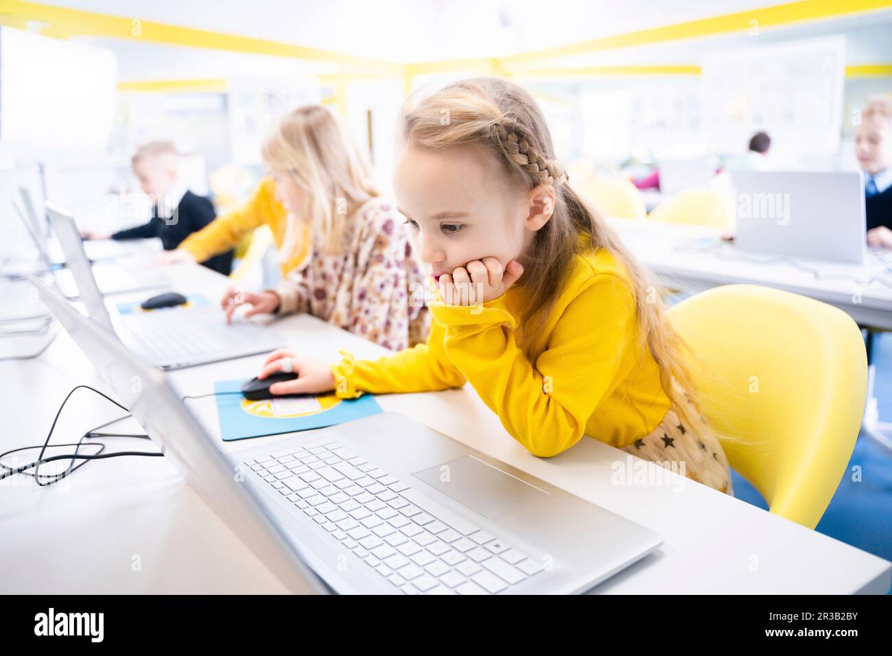 Blond schoolgirl learning through laptop in computer class Stock Photo ...