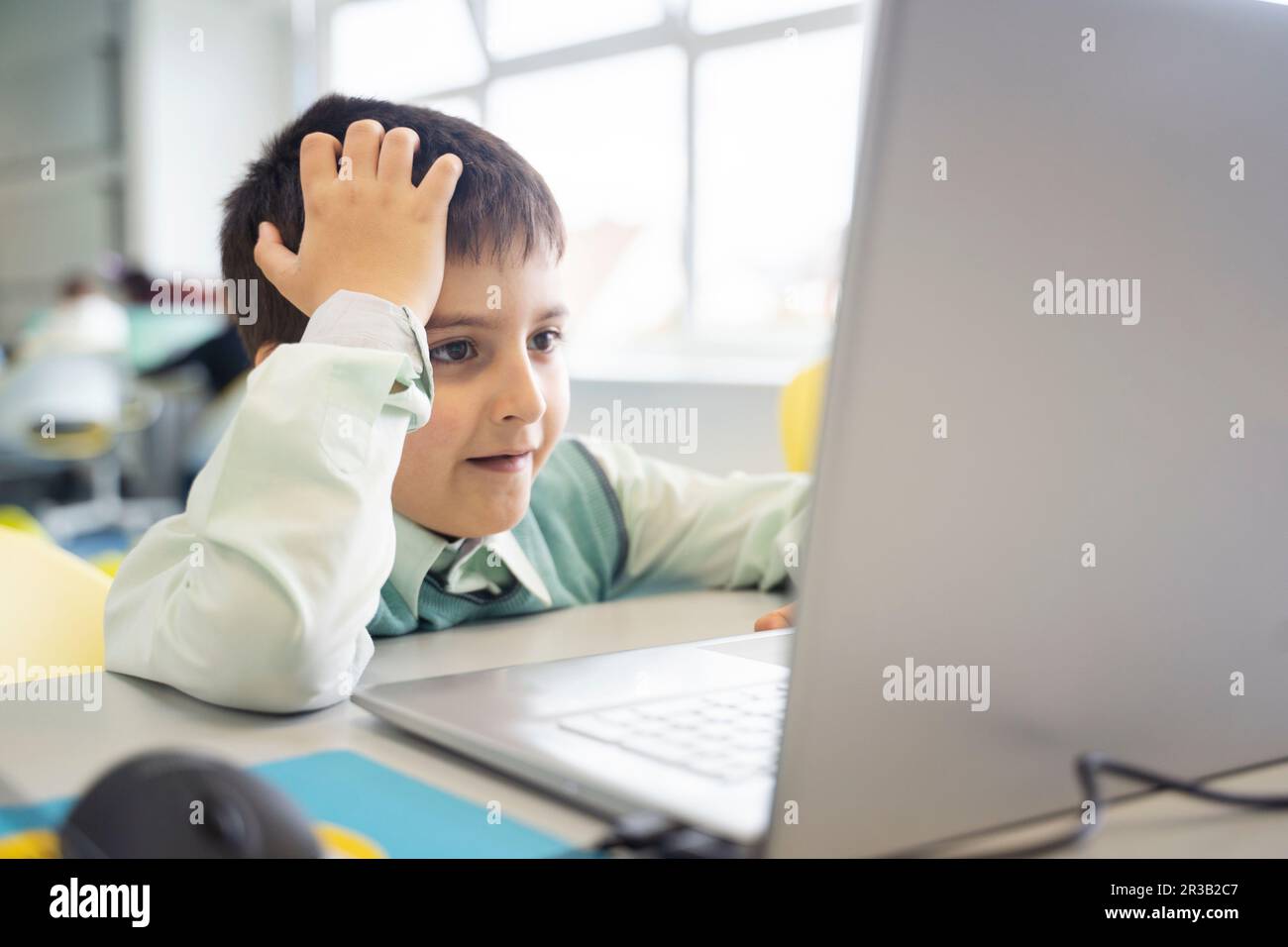 Schoolboy leaning on elbow using laptop in computer class Stock Photo ...