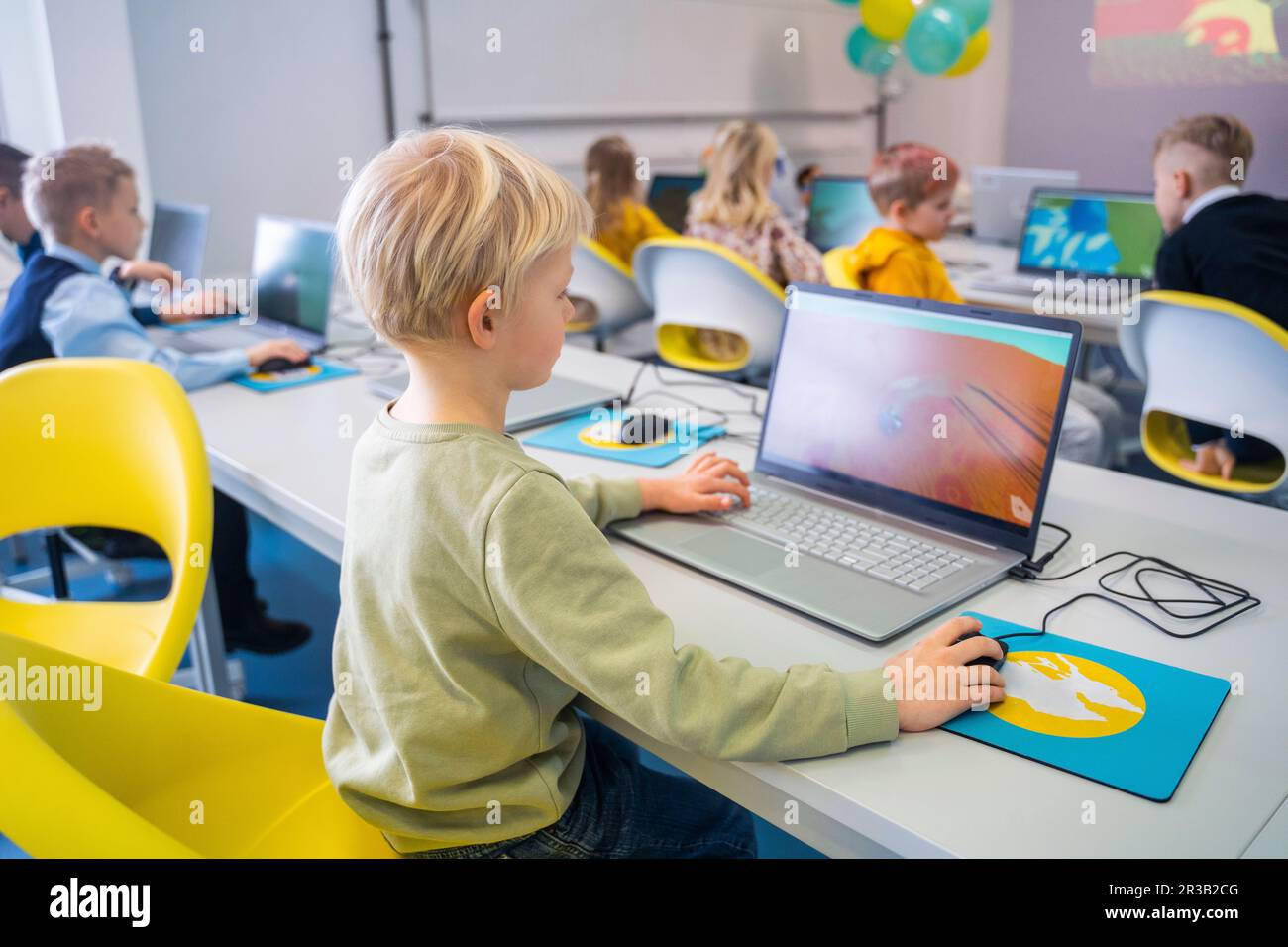Boy studying through laptop sitting in computer class at school Stock ...