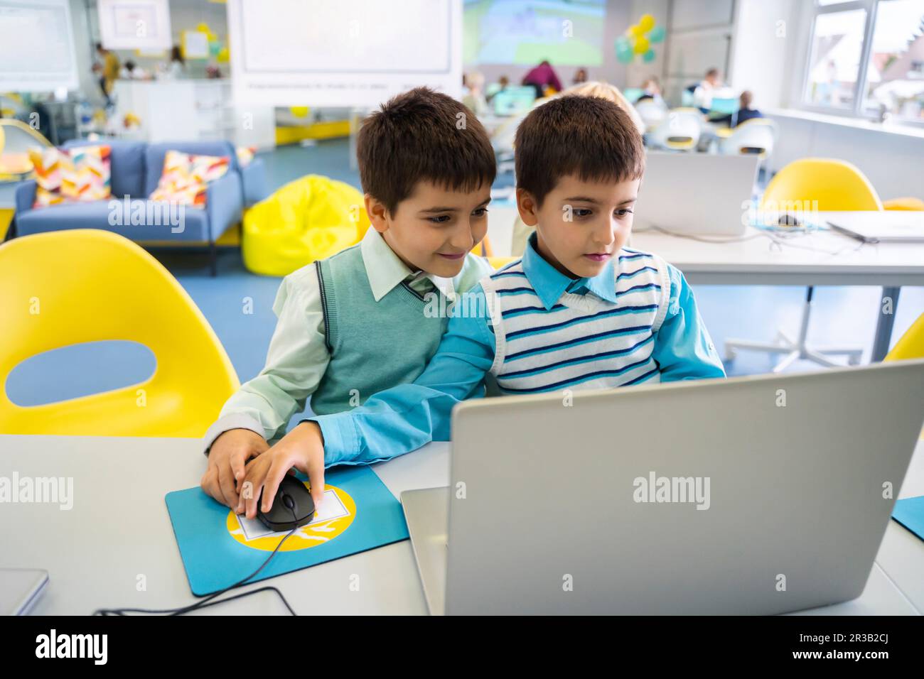 Boys sharing laptop sitting in computer class at school Stock Photo - Alamy