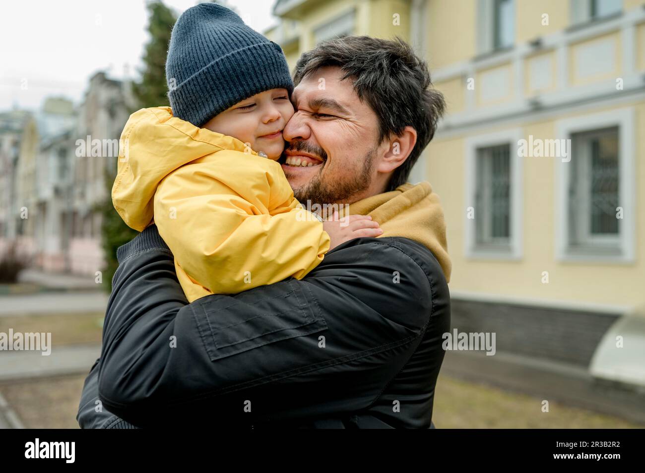 Happy father embracing son wearing knit hat Stock Photo - Alamy
