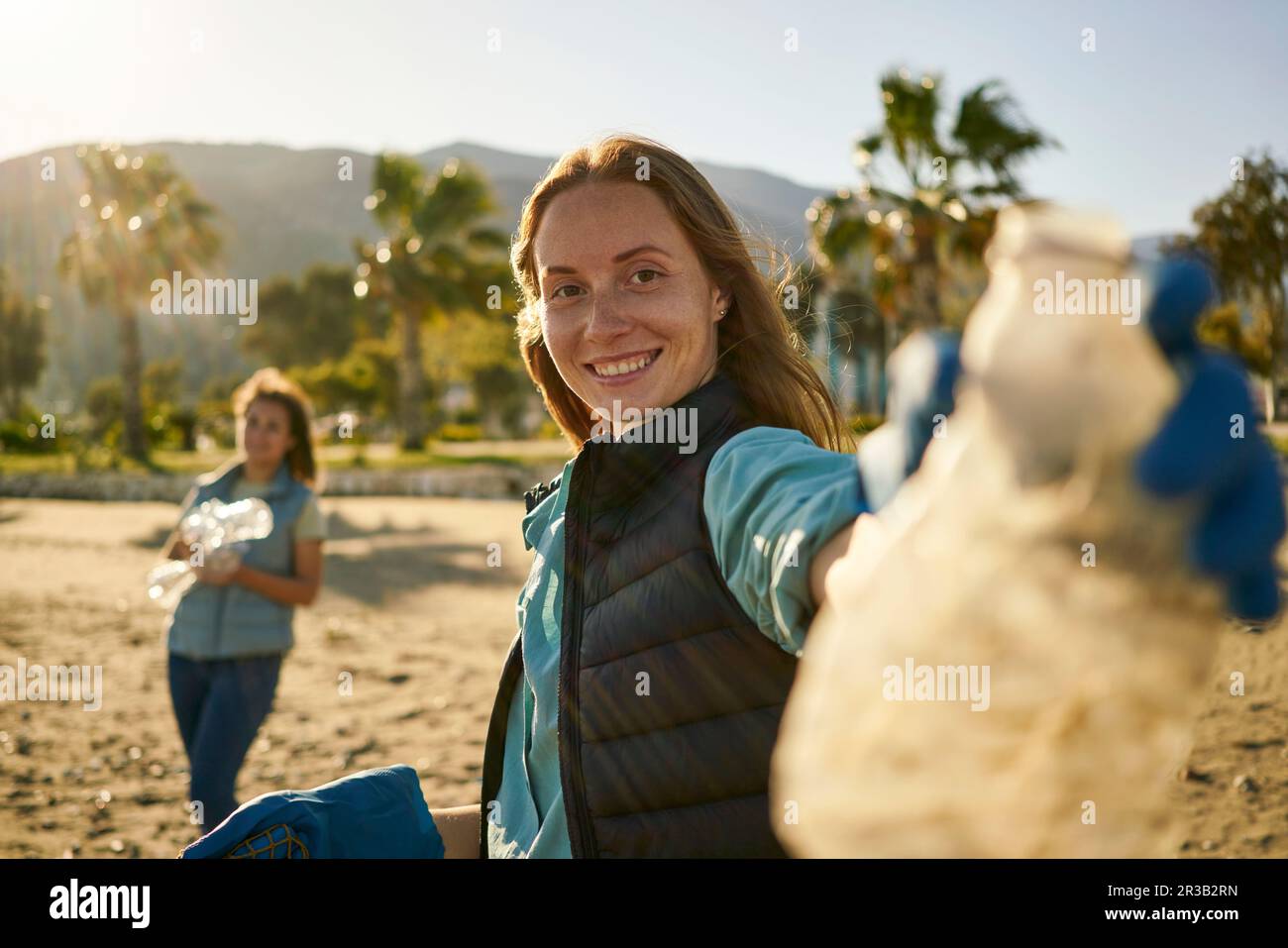 Happy environmentalist holding empty plastic bottle at beach Stock ...