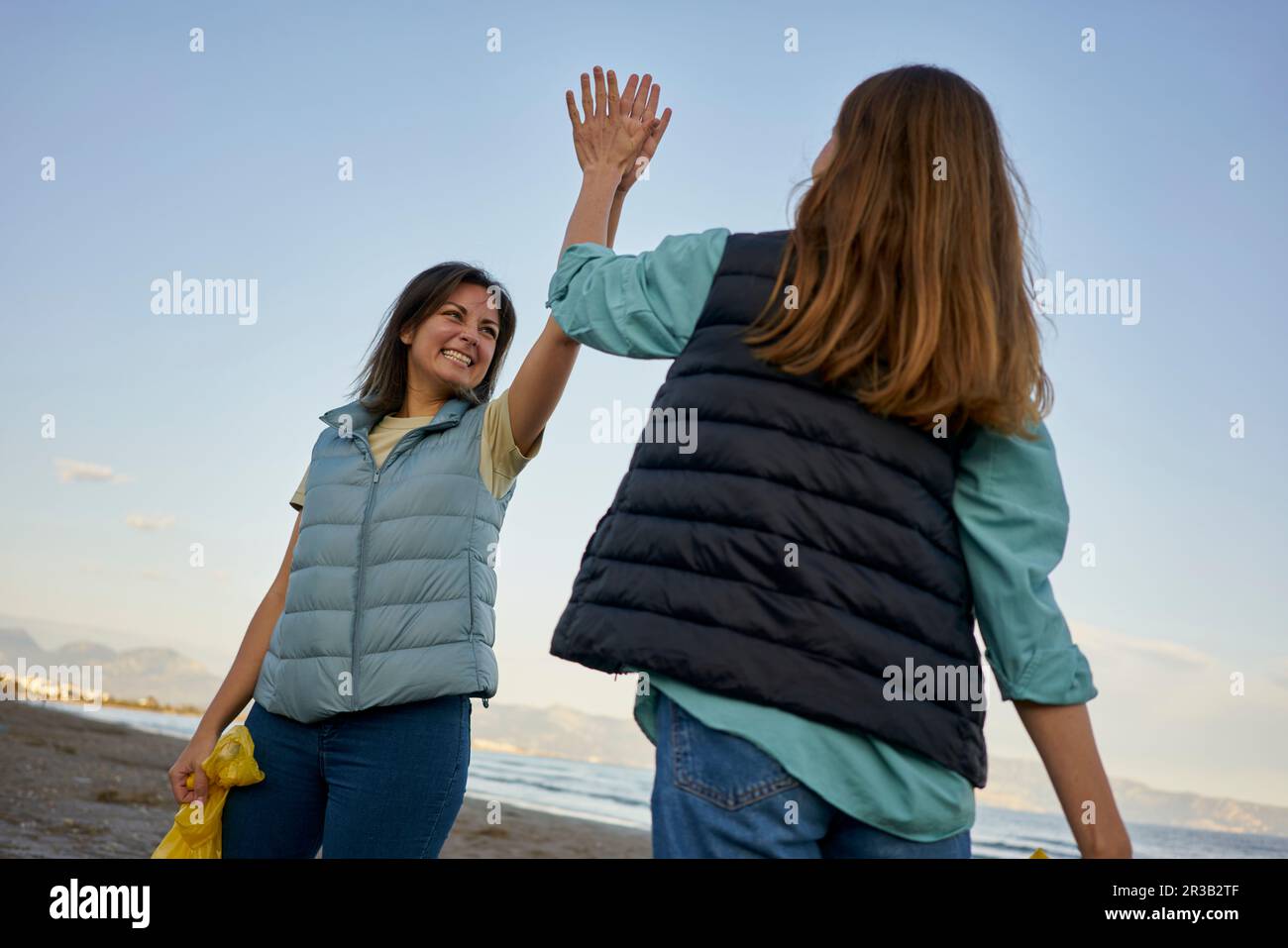 Happy activists giving high-five after cleaning beach Stock Photo - Alamy