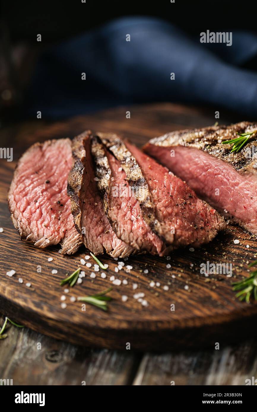 Juicy medium Beef Rib Eye steak slices on wooden board with herbs ...