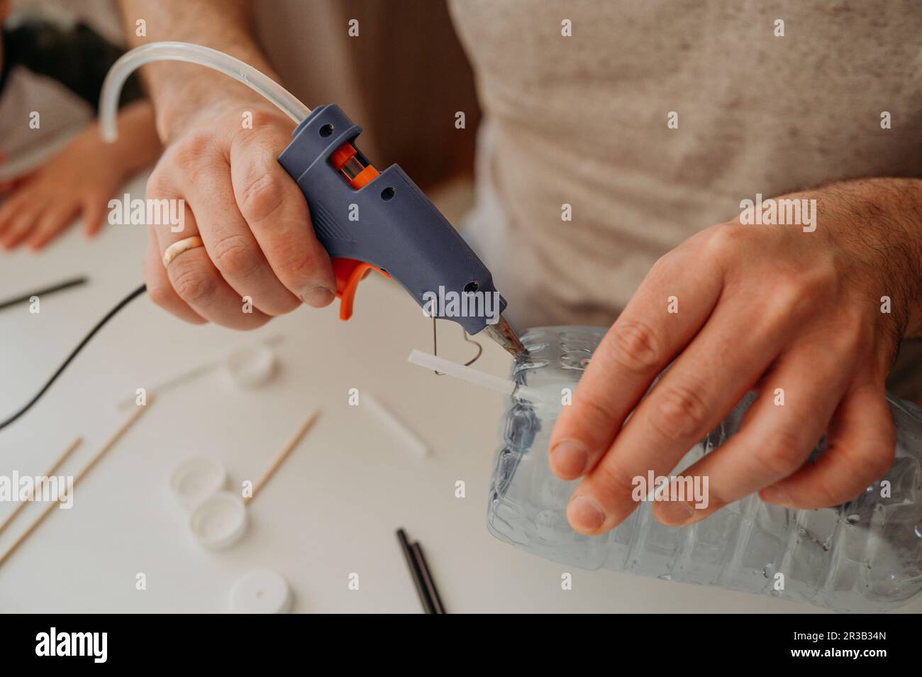 Father using hot glue gun for making plastic car at home Stock Photo ...