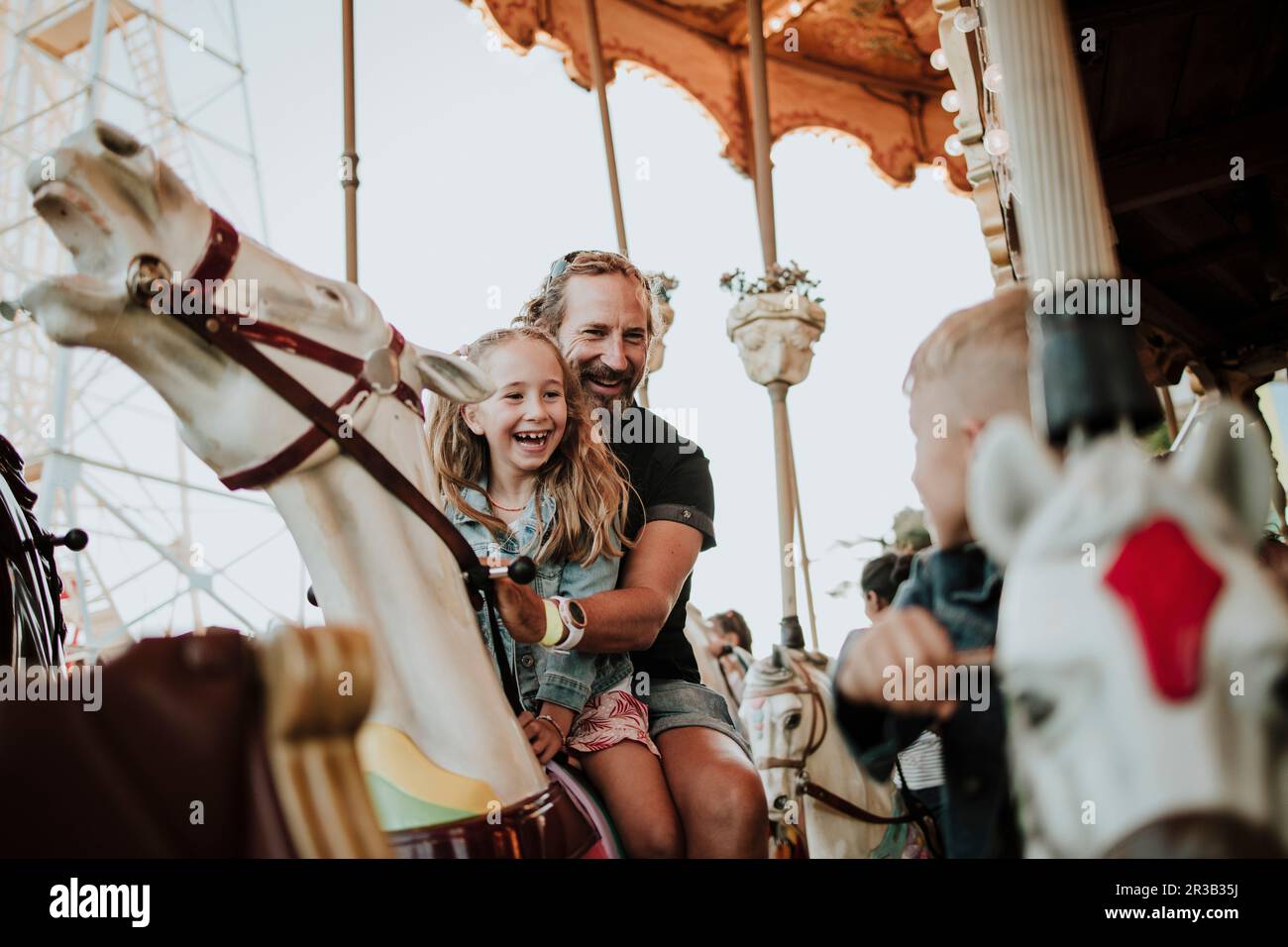 Happy girl enjoying carousel ride with father at amusement park Stock ...