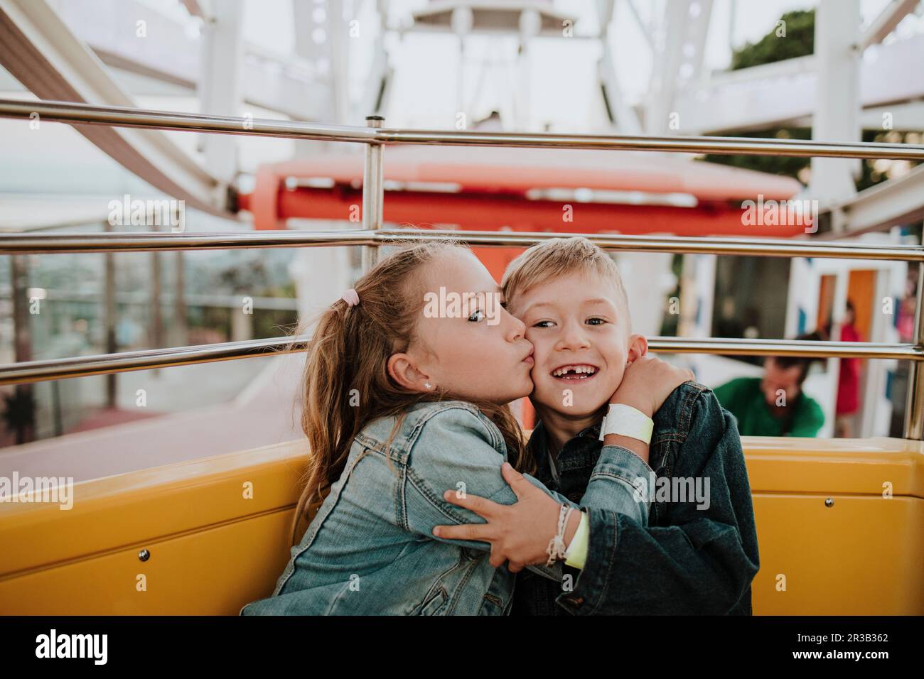 Girl kissing brother sitting in ferris wheel at amusement park Stock ...