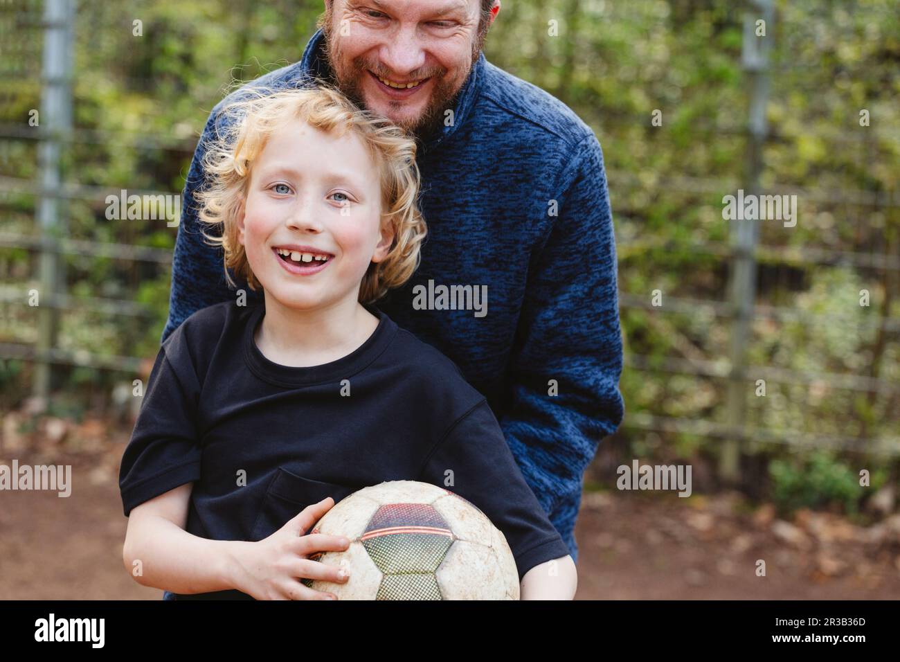 Father embracing happy son holding soccer ball Stock Photo - Alamy