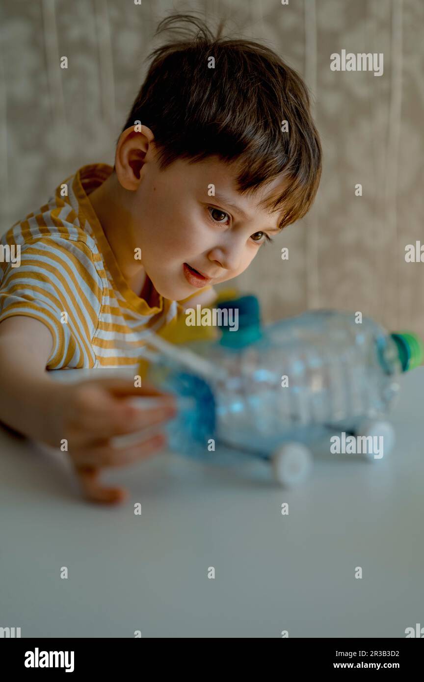 Boy making car from plastic bottle at home Stock Photo - Alamy