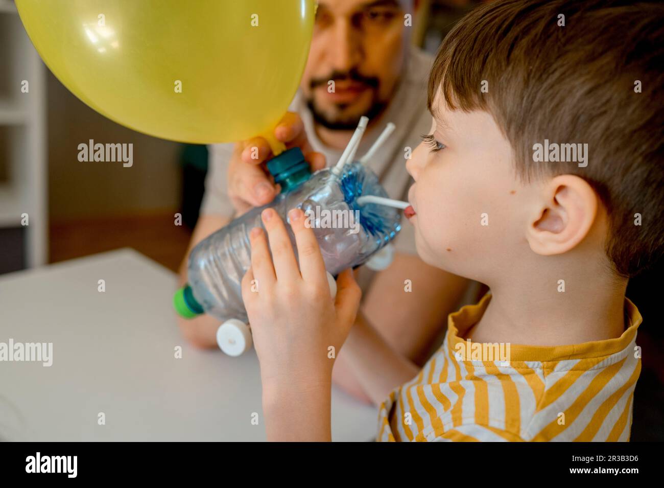 Boy blowing balloon from plastic car bottle at home Stock Photo - Alamy