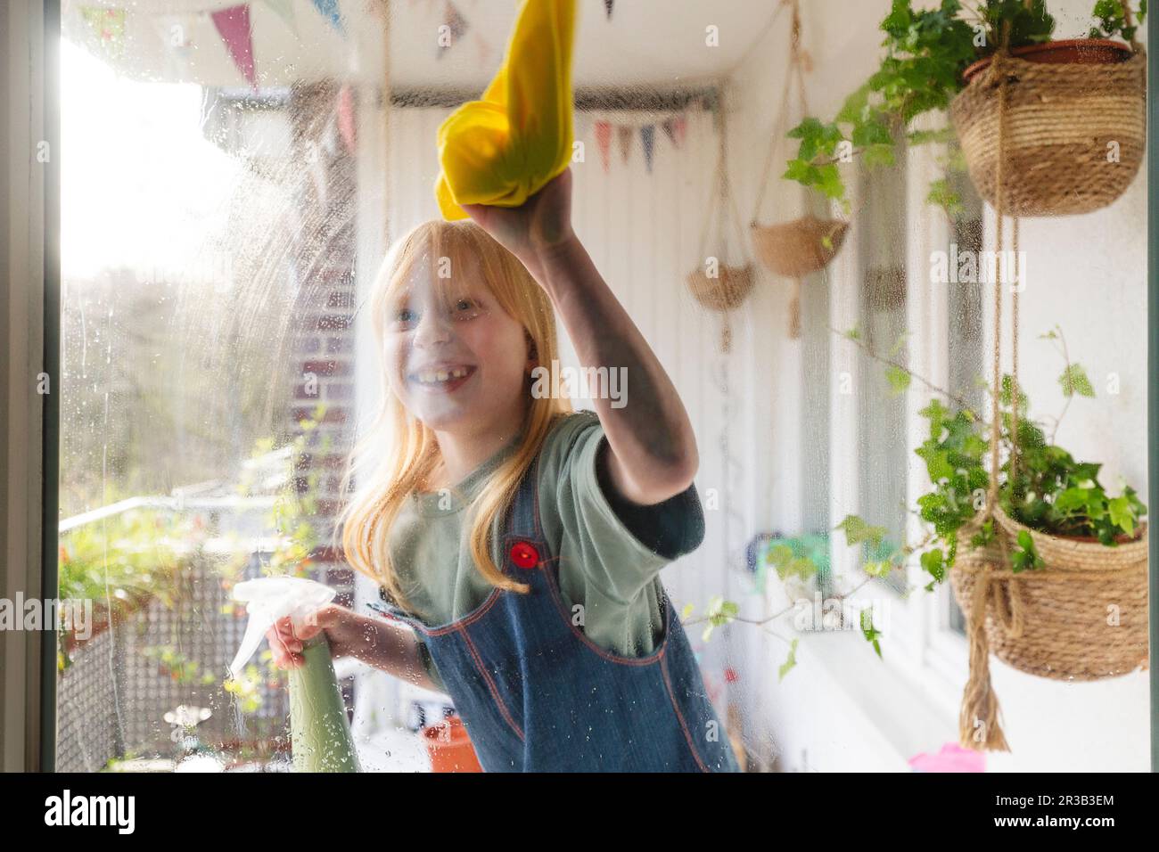 Happy girl cleaning glass window from balcony Stock Photo - Alamy