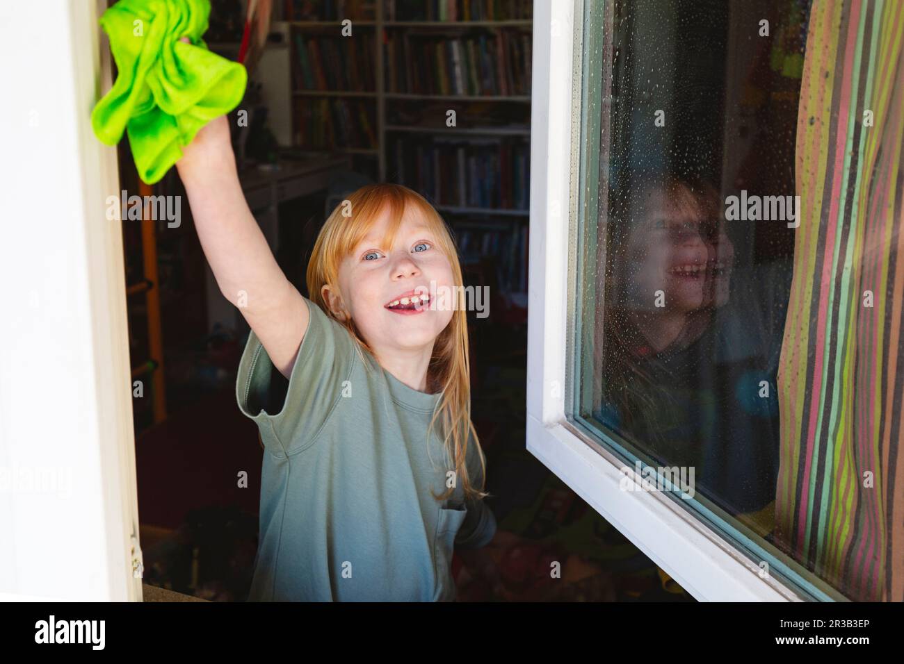 Smiling girl cleaning window at home Stock Photo - Alamy