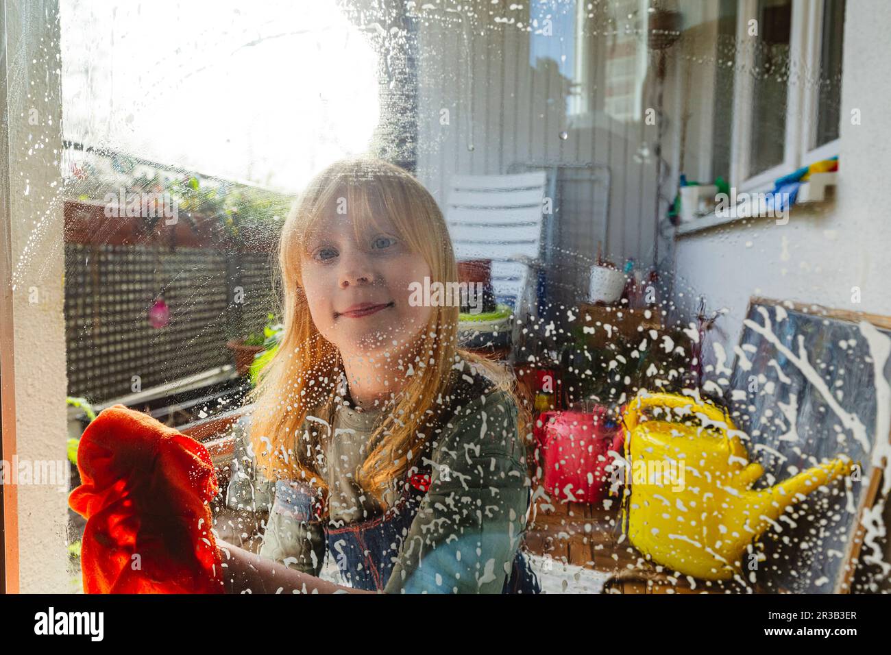 Smiling redhead girl wiping window glass Stock Photo - Alamy