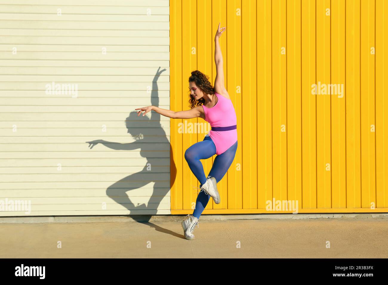 Young dancer showing ballet moves in front of yellow wall Stock Photo ...