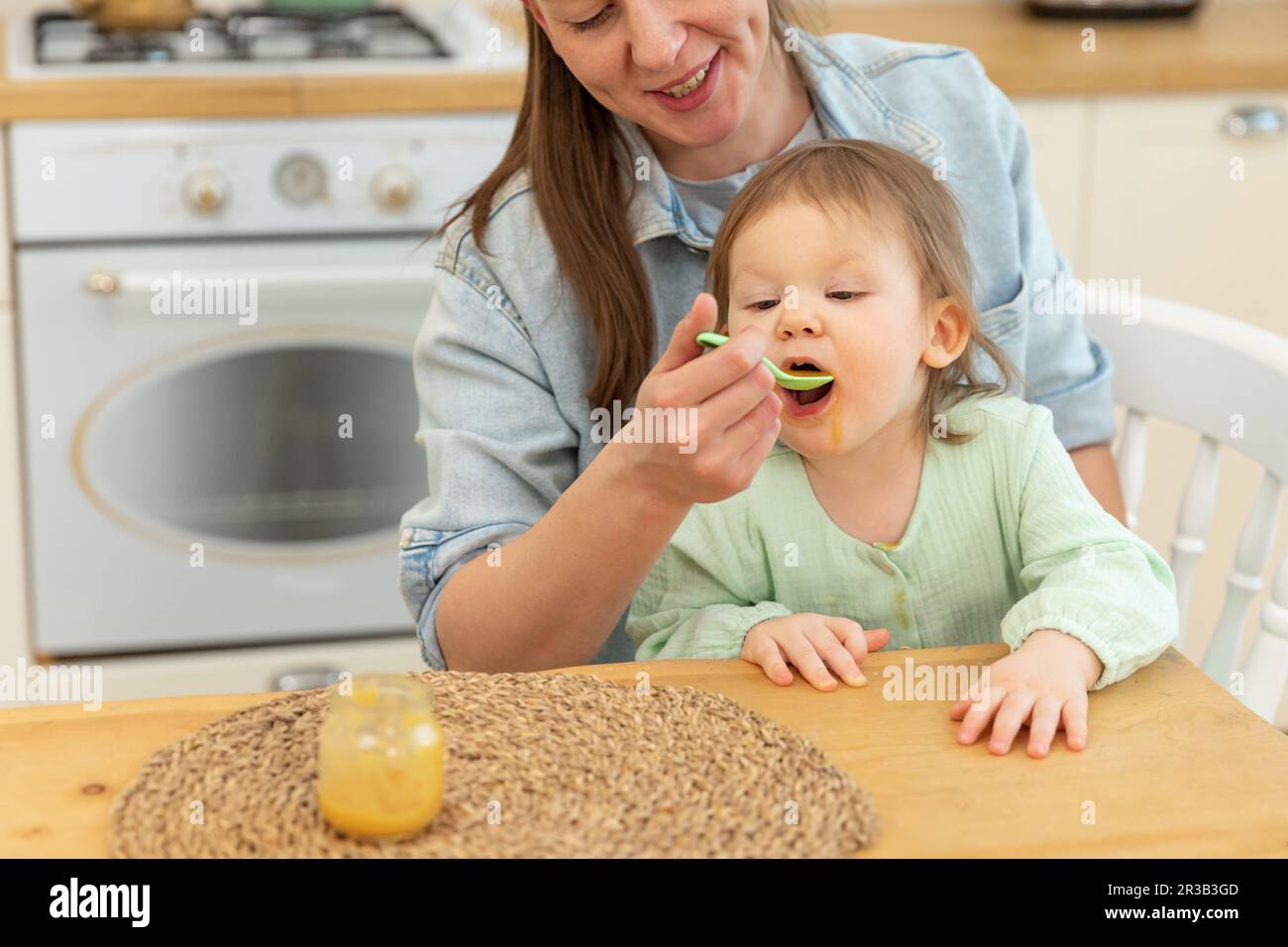Happy family at home. Mother feeding her baby girl from spoon in ...