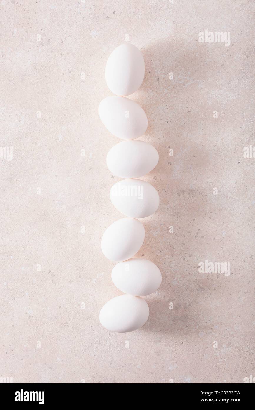 Seven white hen's eggs in a row on a light surface Stock Photo - Alamy