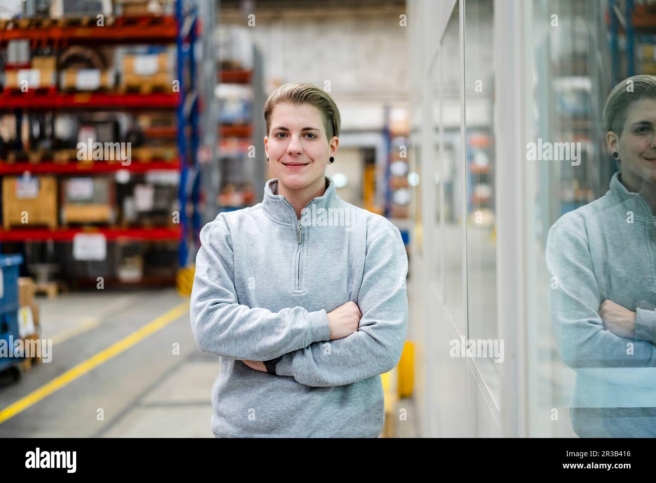 Smiling young employee with arms crossed standing in industry Stock ...