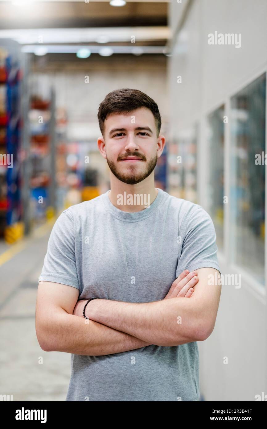 Smiling young employee with arms crossed standing at factory Stock ...