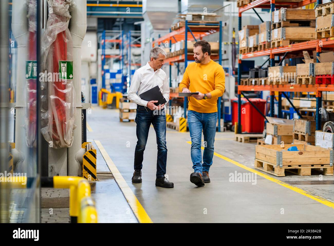 Manager and businessman walking together in production hall at factory ...