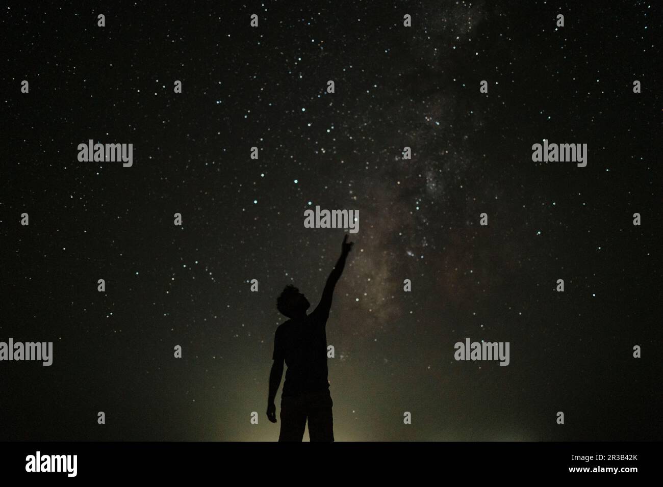 Silhouette of young man pointing towards stars Stock Photo - Alamy