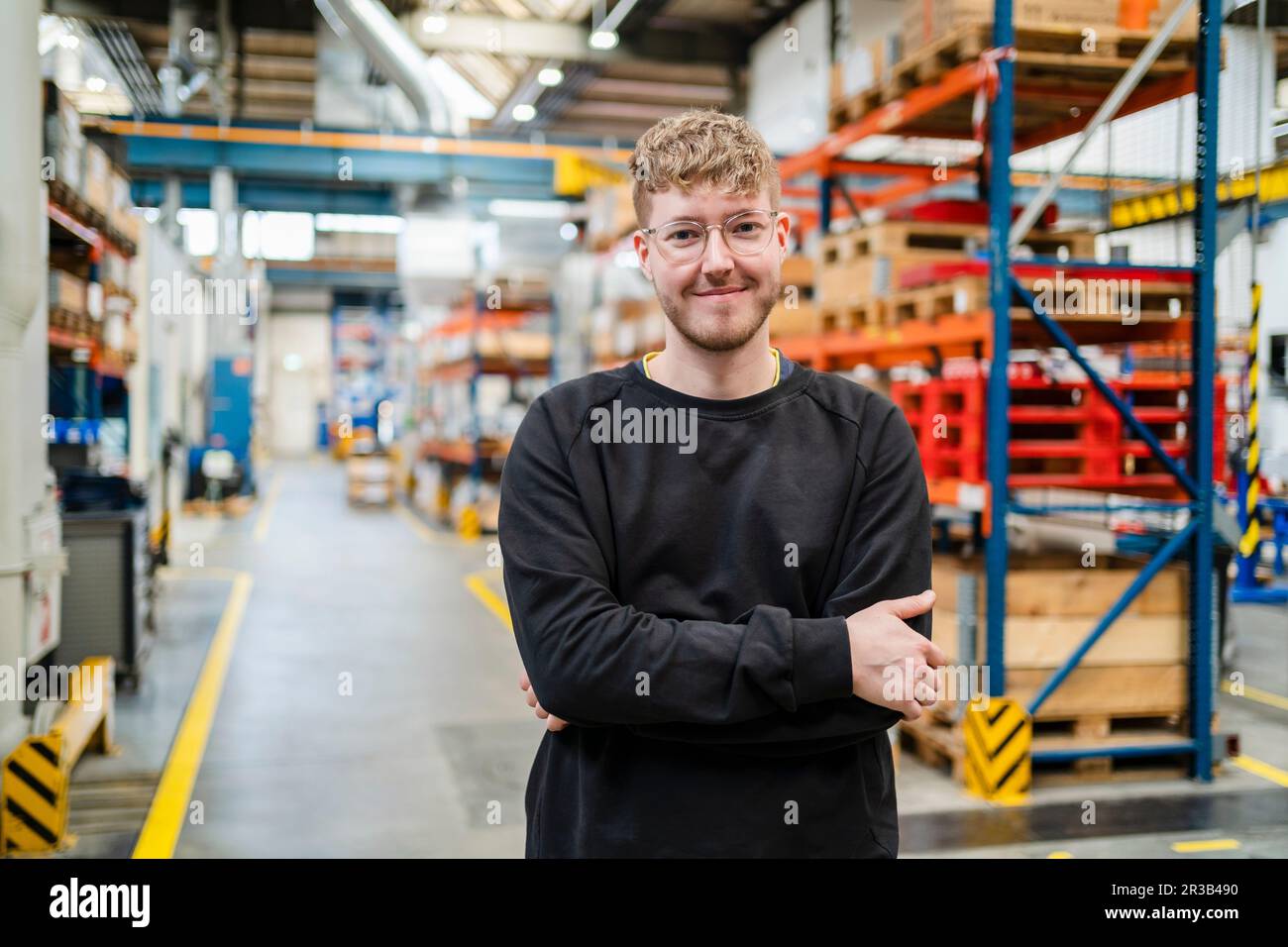 Smiling young employee with arms crossed at factory Stock Photo - Alamy