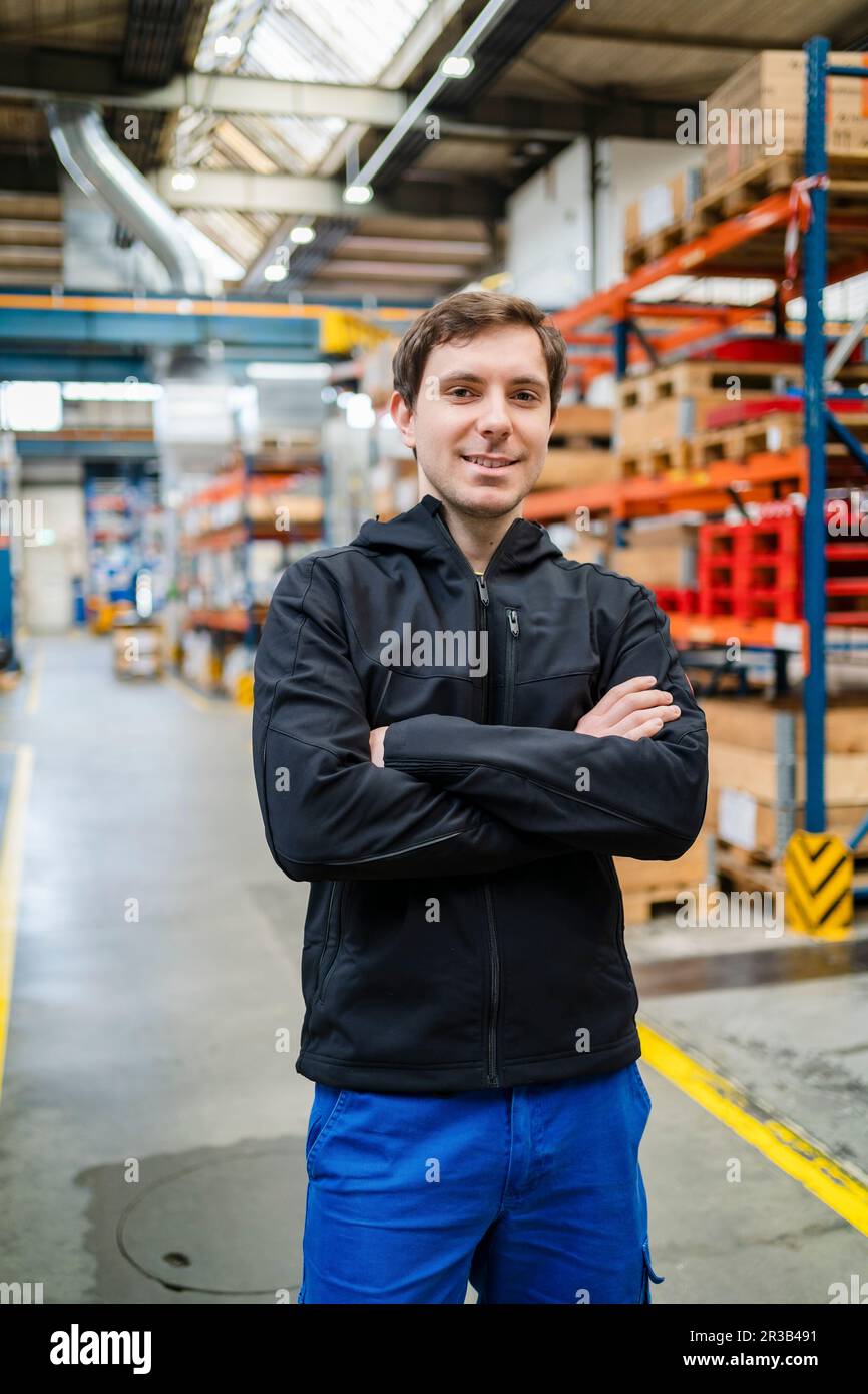 Smiling employee with arms crossed standing in factory Stock Photo - Alamy