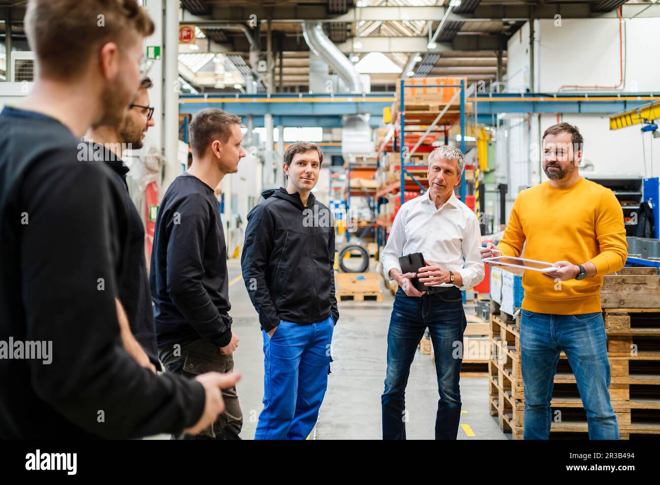 Manager conducting meeting with employees in factory Stock Photo - Alamy