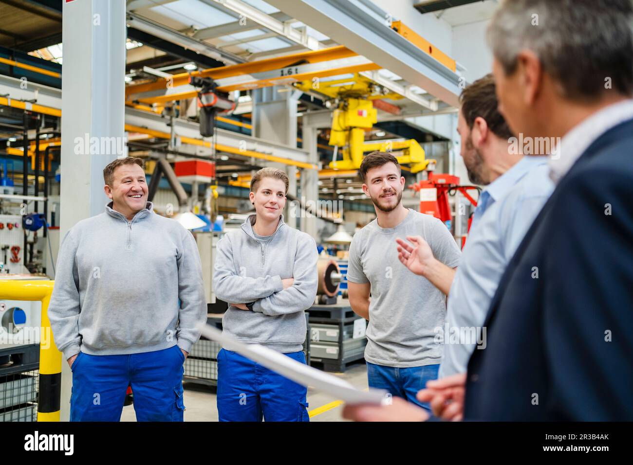 Manager explaining to employees in meeting at factory Stock Photo - Alamy