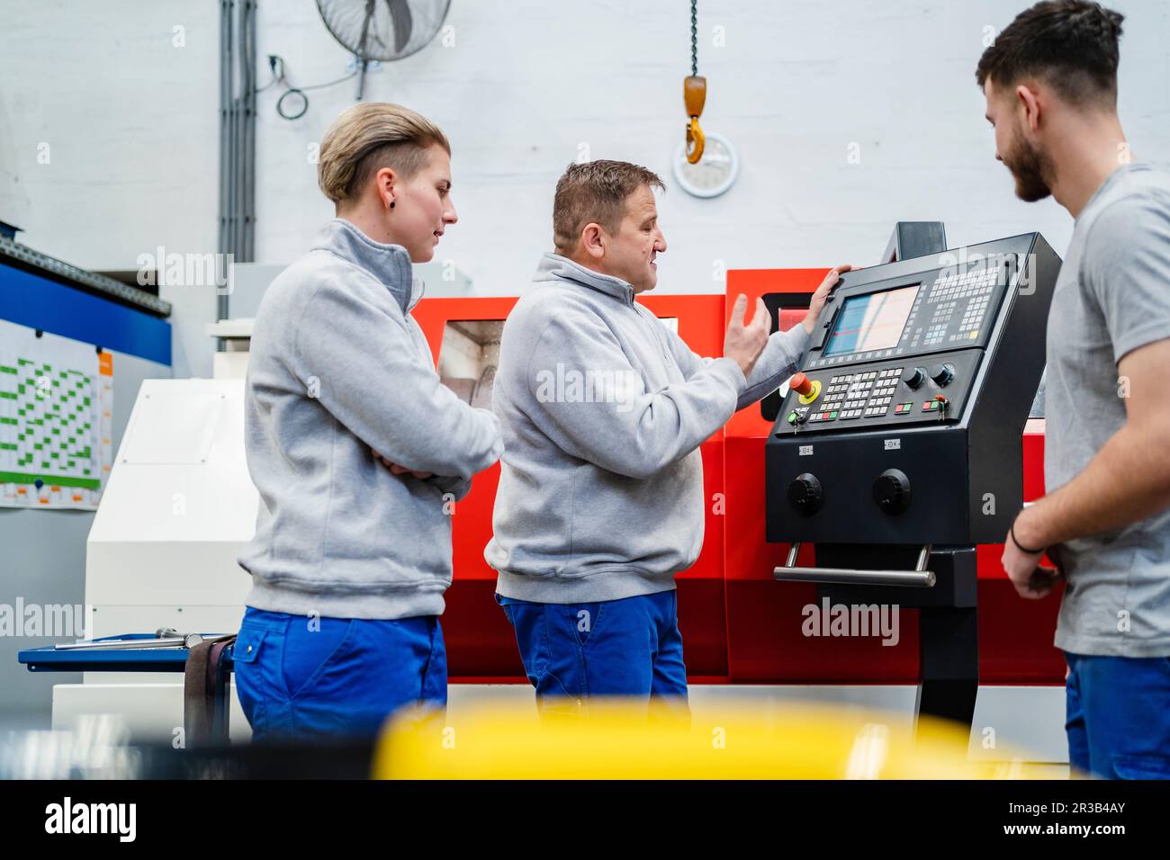 Employee explaining CNC machine to colleagues at factory Stock Photo ...