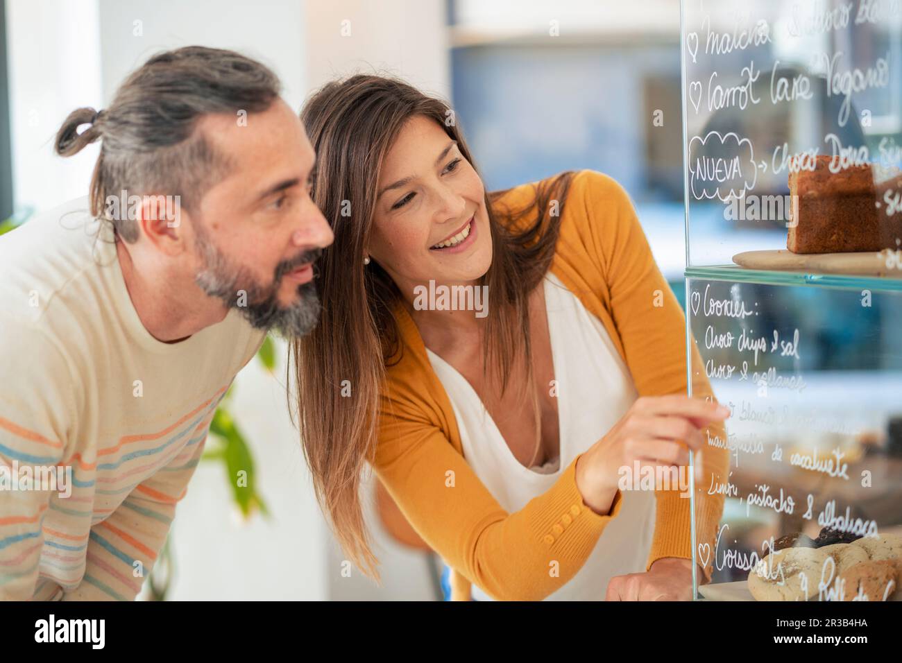 Excited couple selecting food from display at cafe Stock Photo - Alamy